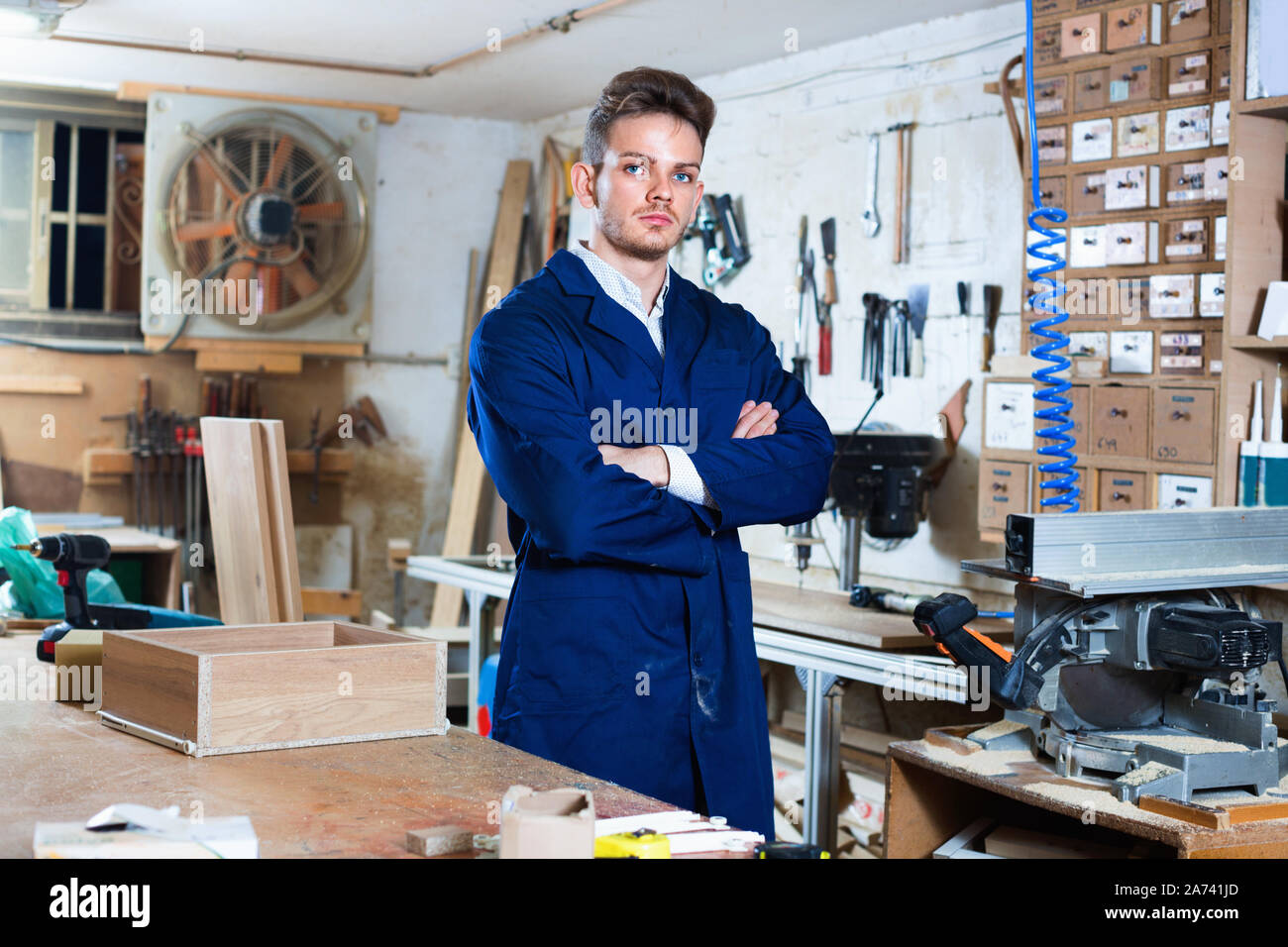 Glad cheerful positive guy displaying his workplace and tools at ...