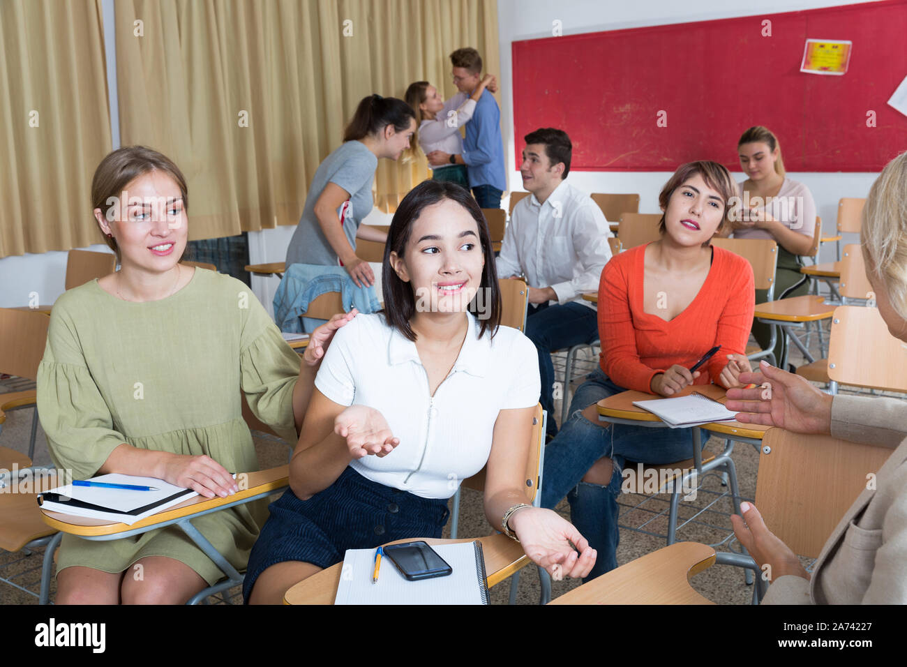 Happy group of adult students lively chatting while enjoying free time ...