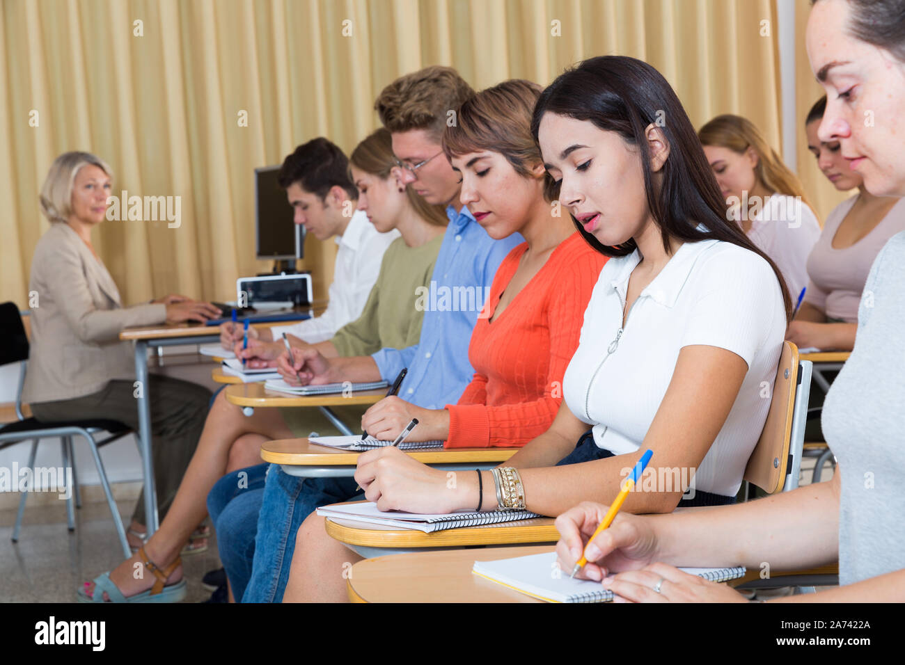Side view of student group working with female teacher on lecture in ...