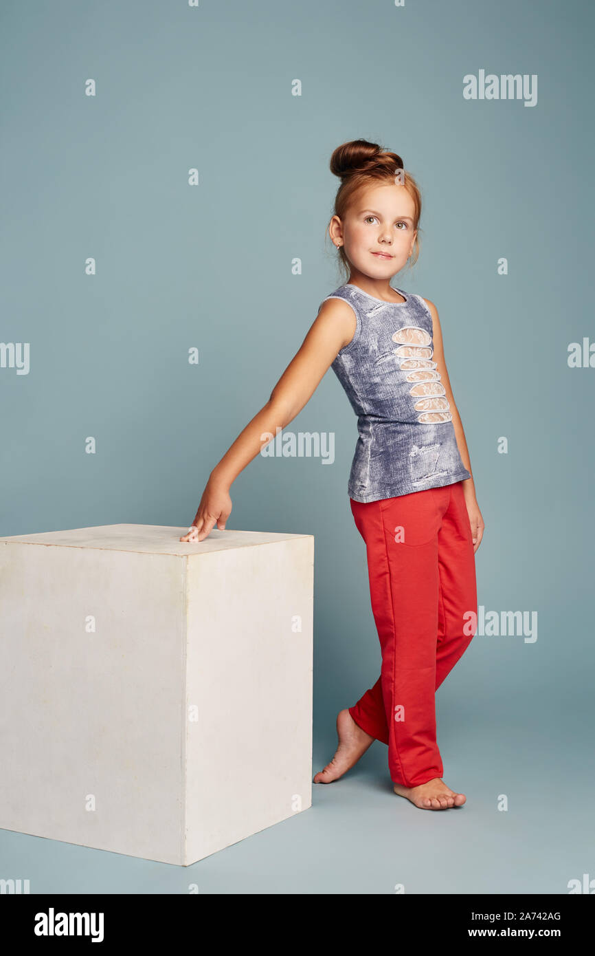 Brooding beautiful girl sitting on a white cube and posing, school ...
