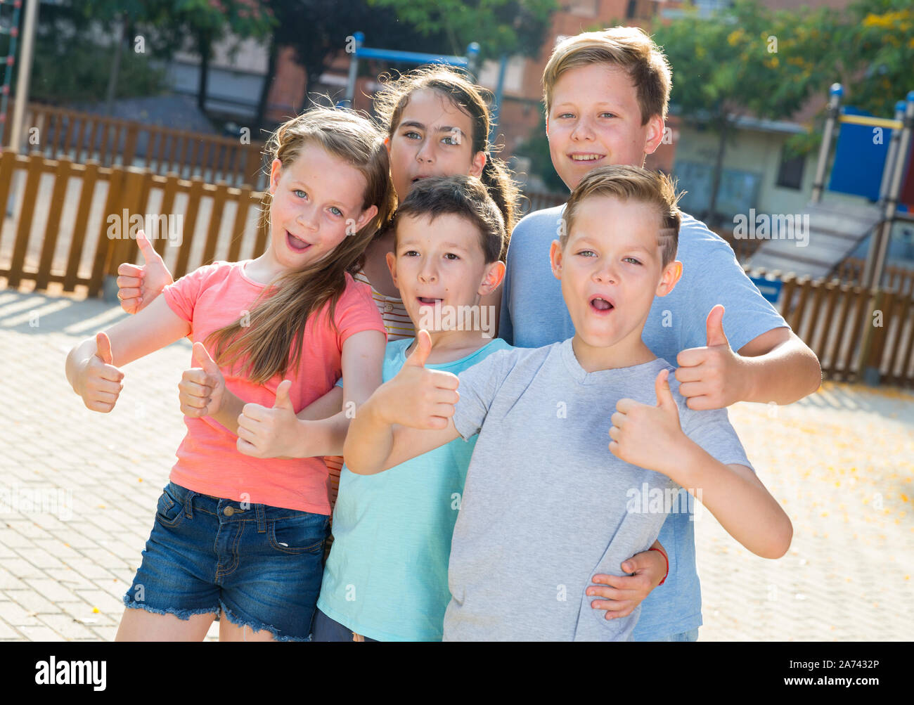 Glad kids posing at the playground together and thumbs up Stock Photo ...