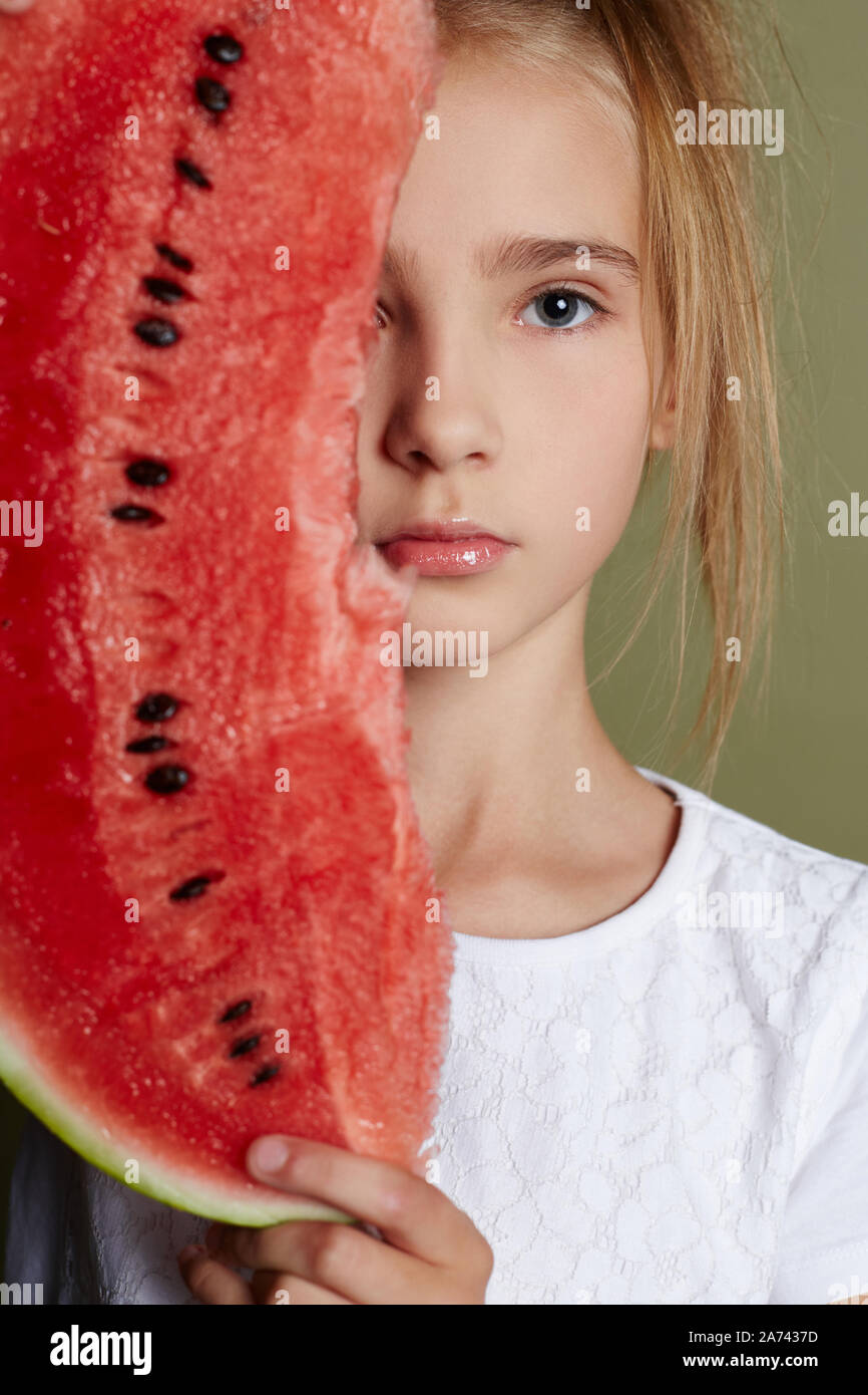 Little girl eats a watermelon on an olive background, bright cheerful ...