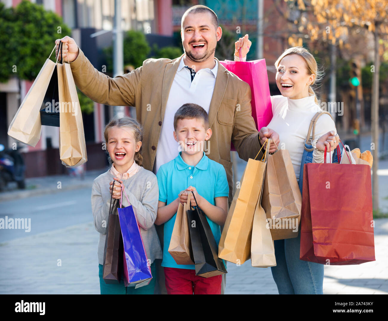 Young happy parents with two teenagers going for a shopping outdoors ...