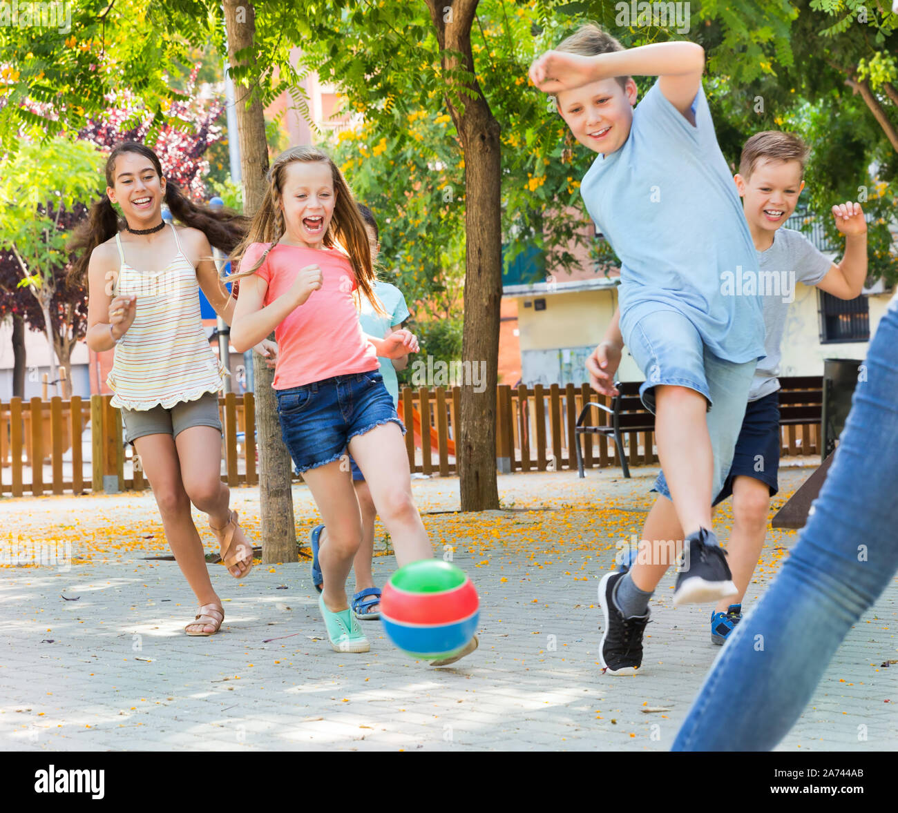 Happy children playfully running after ball Stock Photo - Alamy