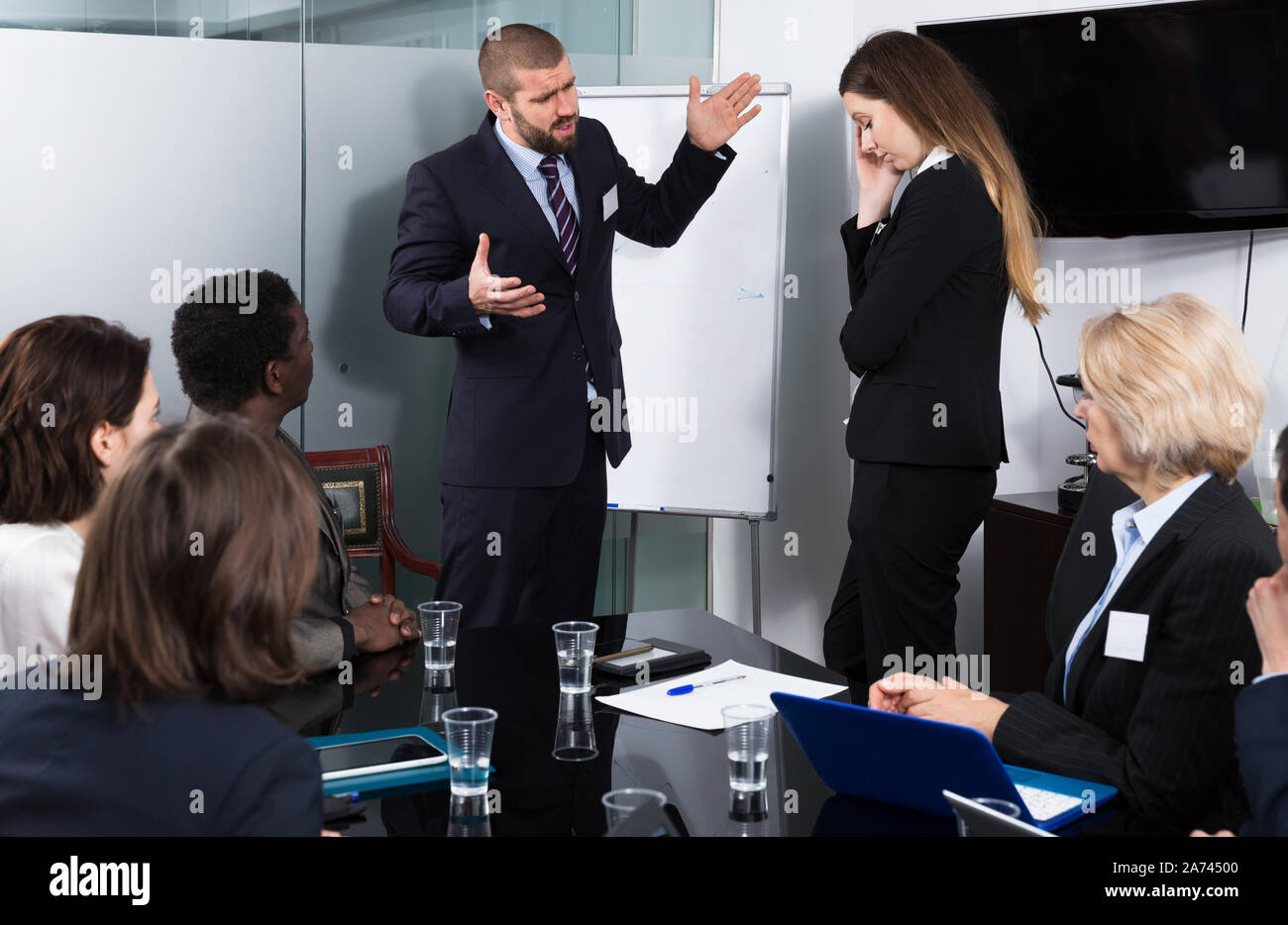 Irritated boss standing near whiteboard in meeting room, scolding ...