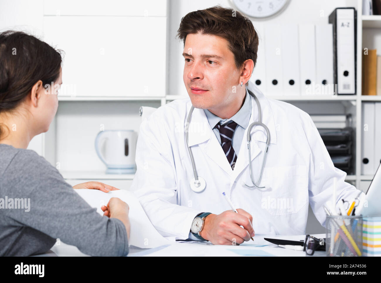 Cheerful positive doctor speaking with client in the medical center ...