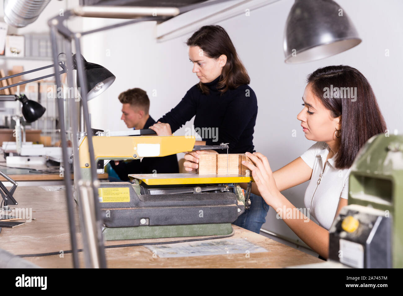 Female student of architecture faculty using scroll saw while engaged ... Female student of architecture faculty using scroll saw while engaged ...
