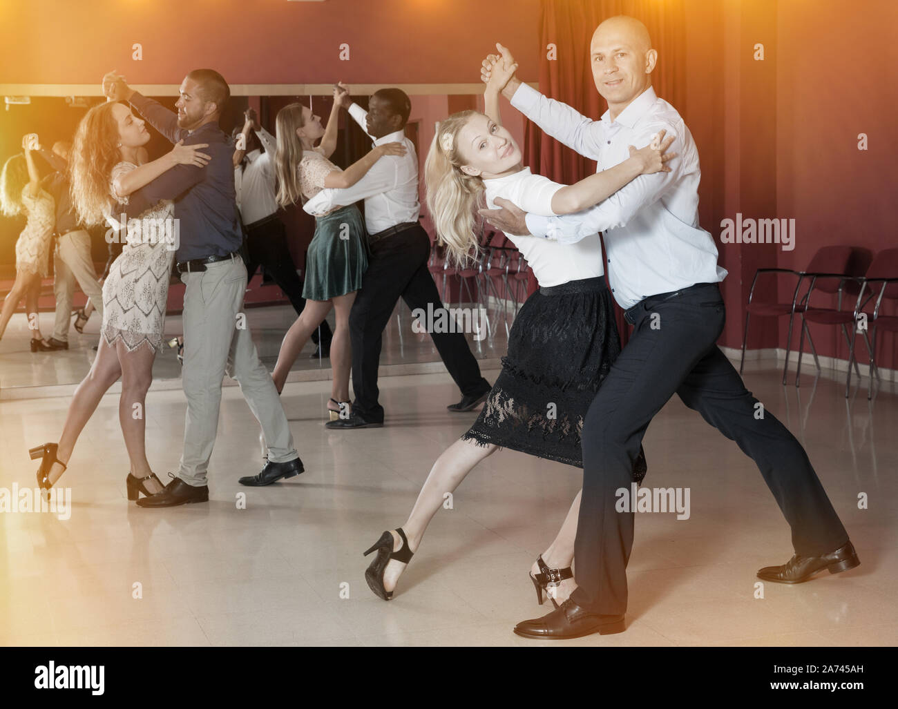 Young positive people dancing together slow ballroom dances in pairs ...