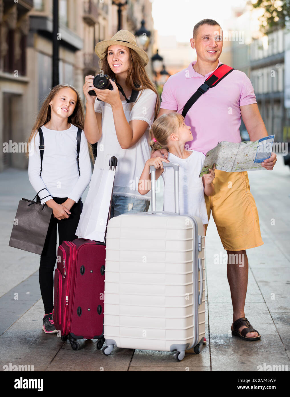 Positive family tourists with children using camera and map during ...