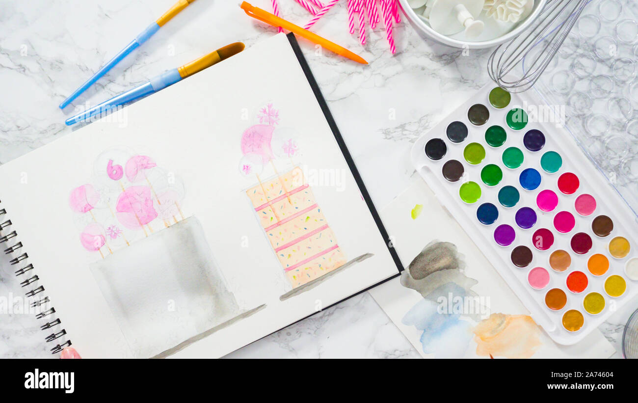 Flat lay. Baker is drawing the design of a birthday cake with ...