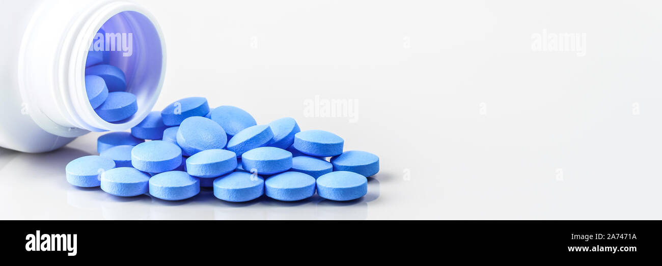 Blue pills are scattered from a jar on a white background Stock Photo ...