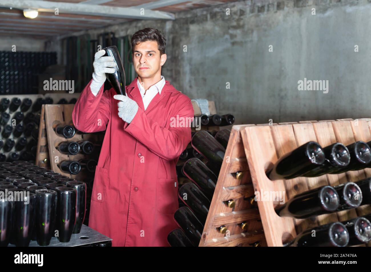 Attentive friendly man winery employee wearing coat working in aging ...