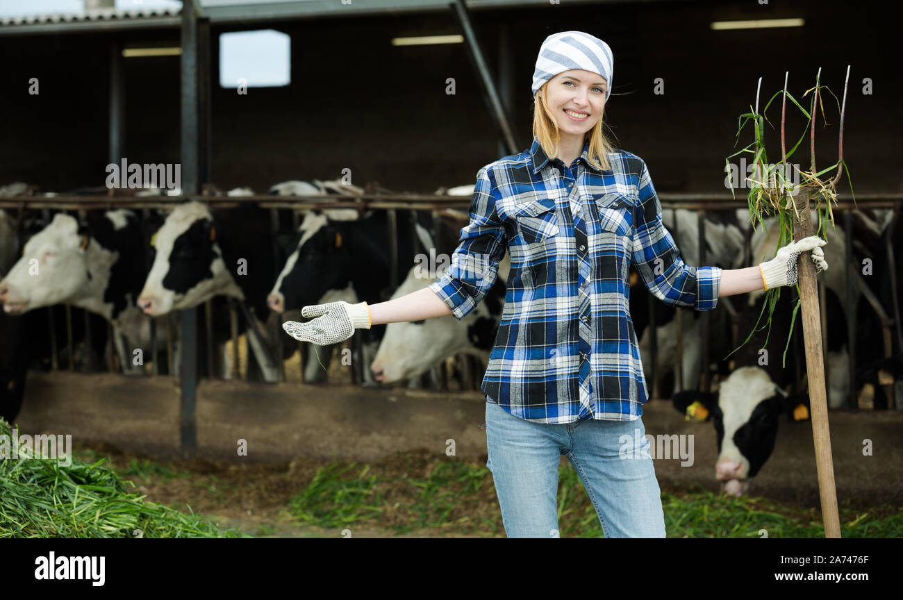 Female cattle-farm worker preparing grass for feeding cows Stock Photo ...