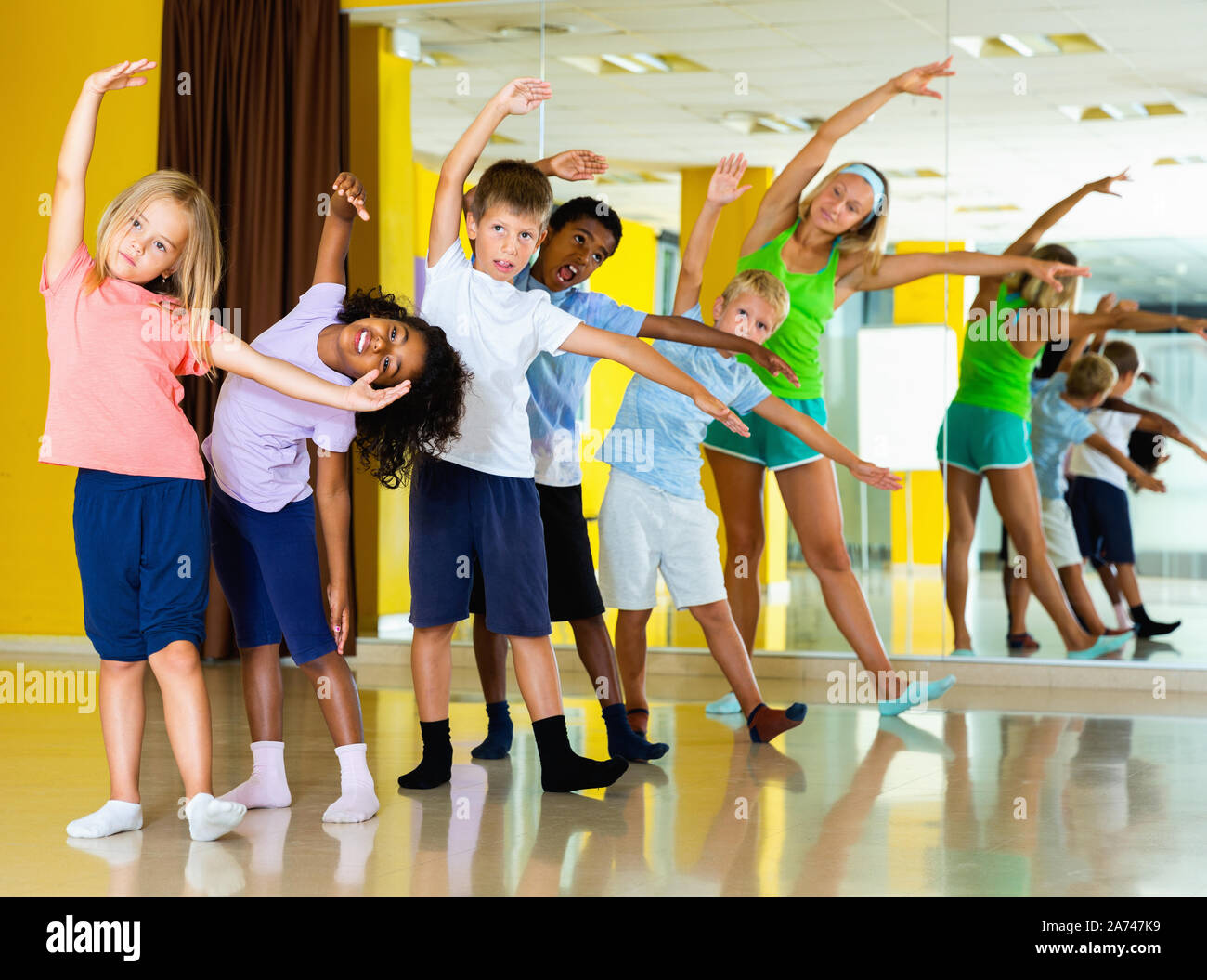 Cheerful positive smiling preteen dancers practicing dance routine with ...