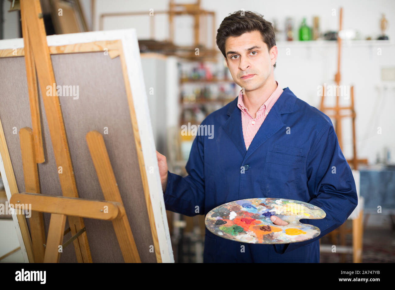 Creative male artist drawing picture with oil paints in studio Stock ...