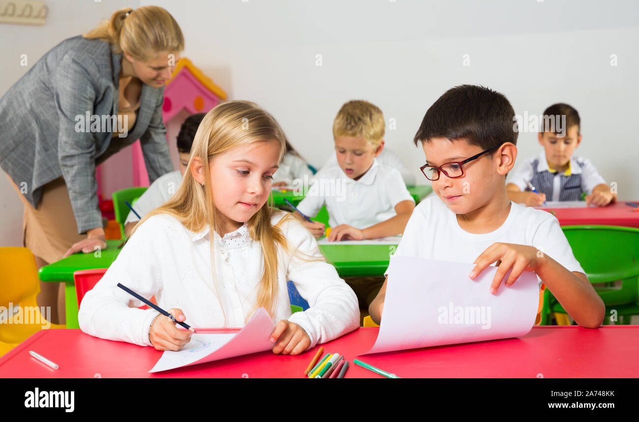 Portrait of schoolchildren sitting in classroom and chatting during ...