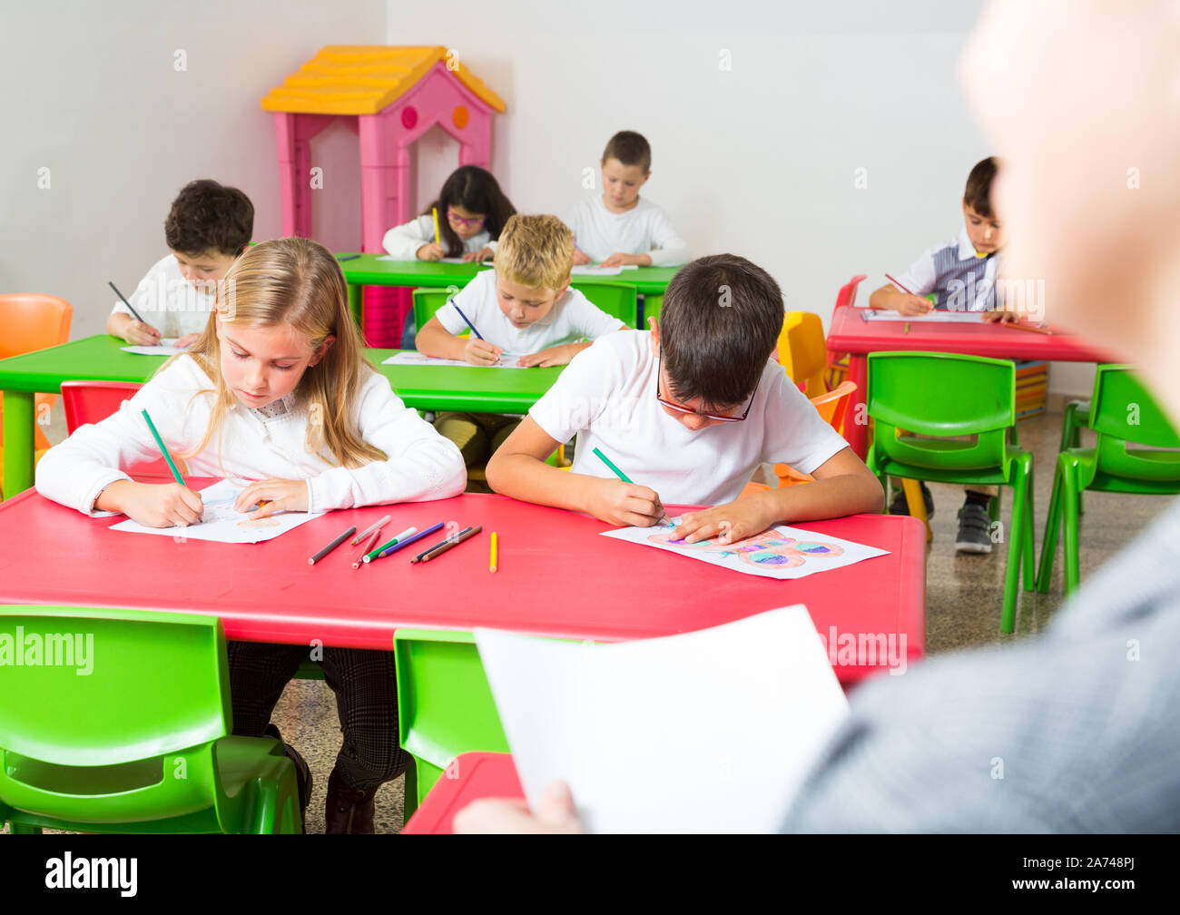 First person view of children at desks in classroom Stock Photo - Alamy