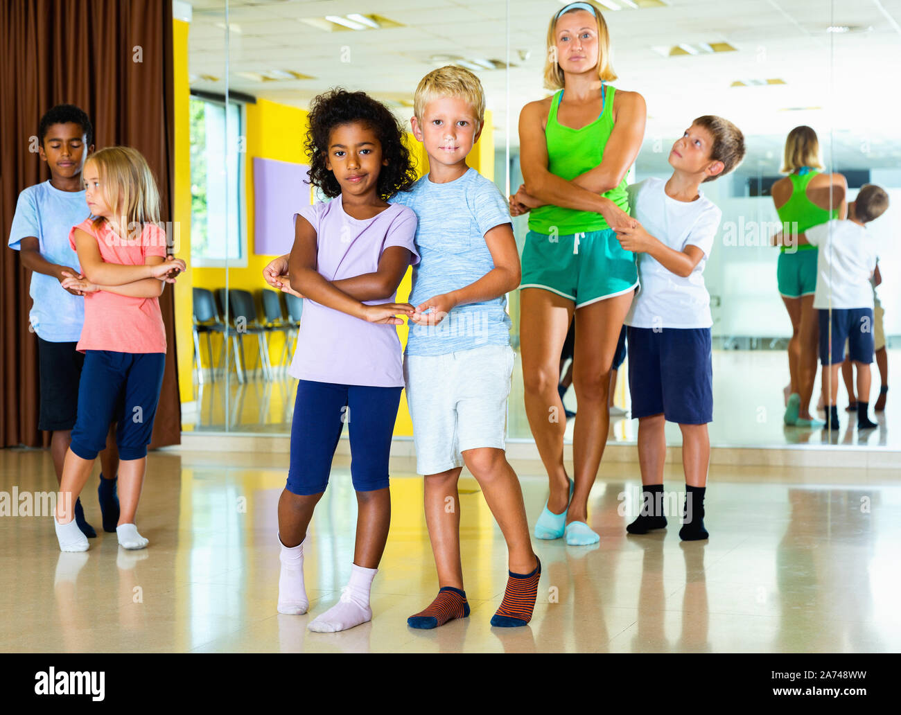 Group of happy cheerful children practicing vigorous jive movements in ...