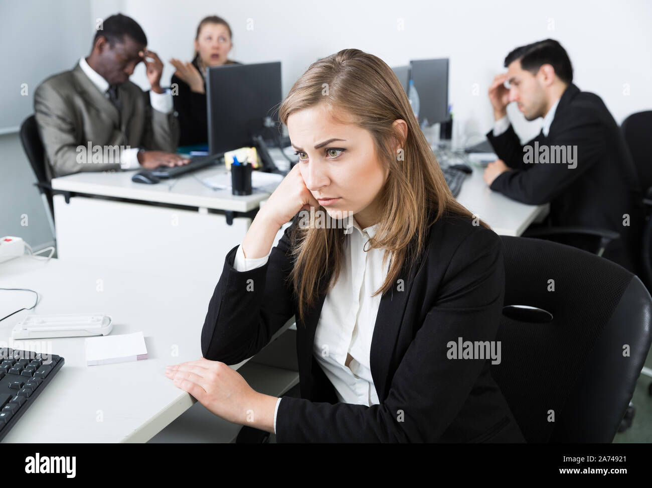 Upset thoughtful girl sitting at workplace in modern coworking space on ...