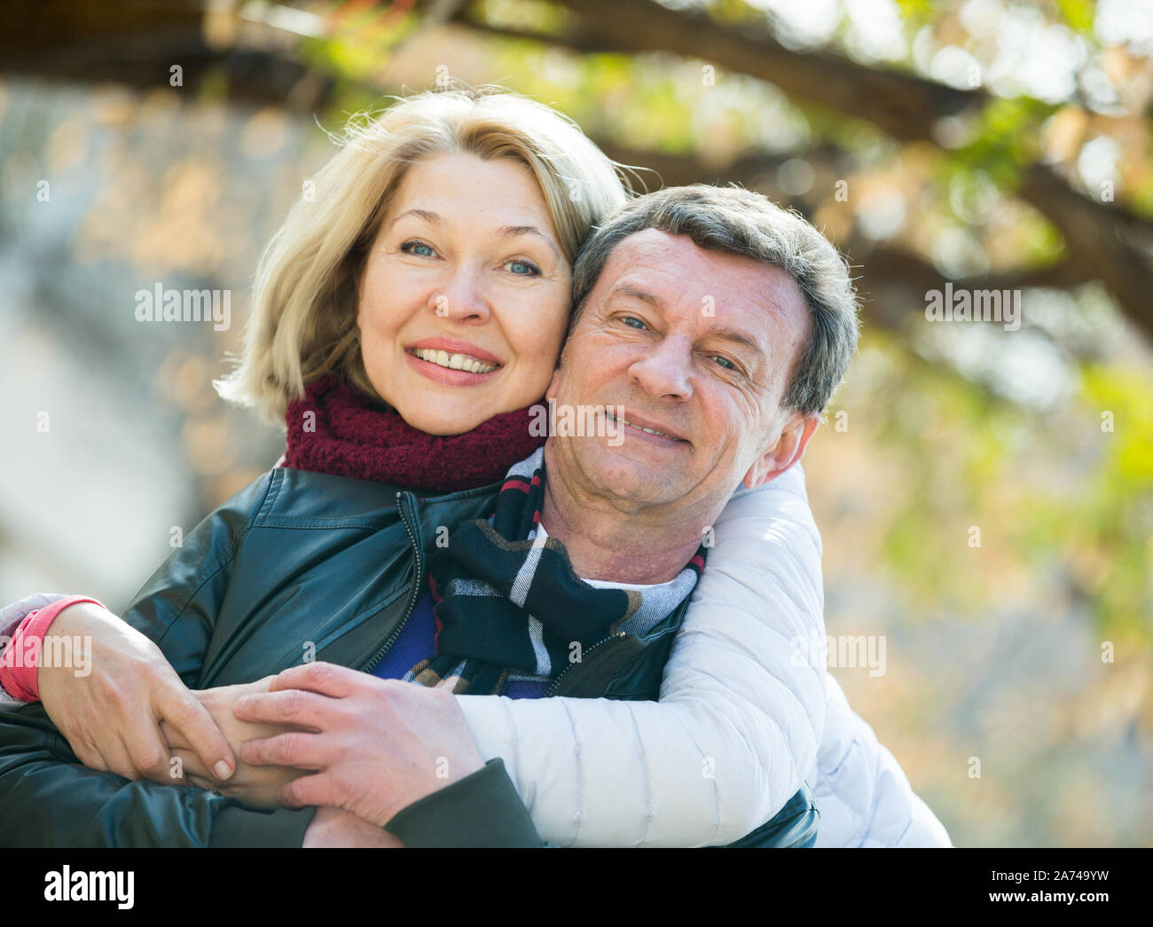 Portrait of senior couple cuddling in park and laughing Stock Photo - Alamy