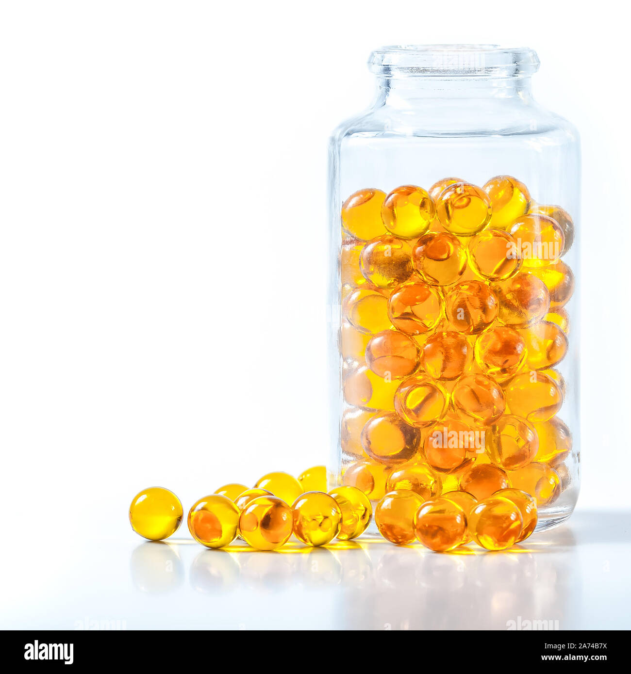 Yellow capsules scattered from a glass jar on a white background Stock ...