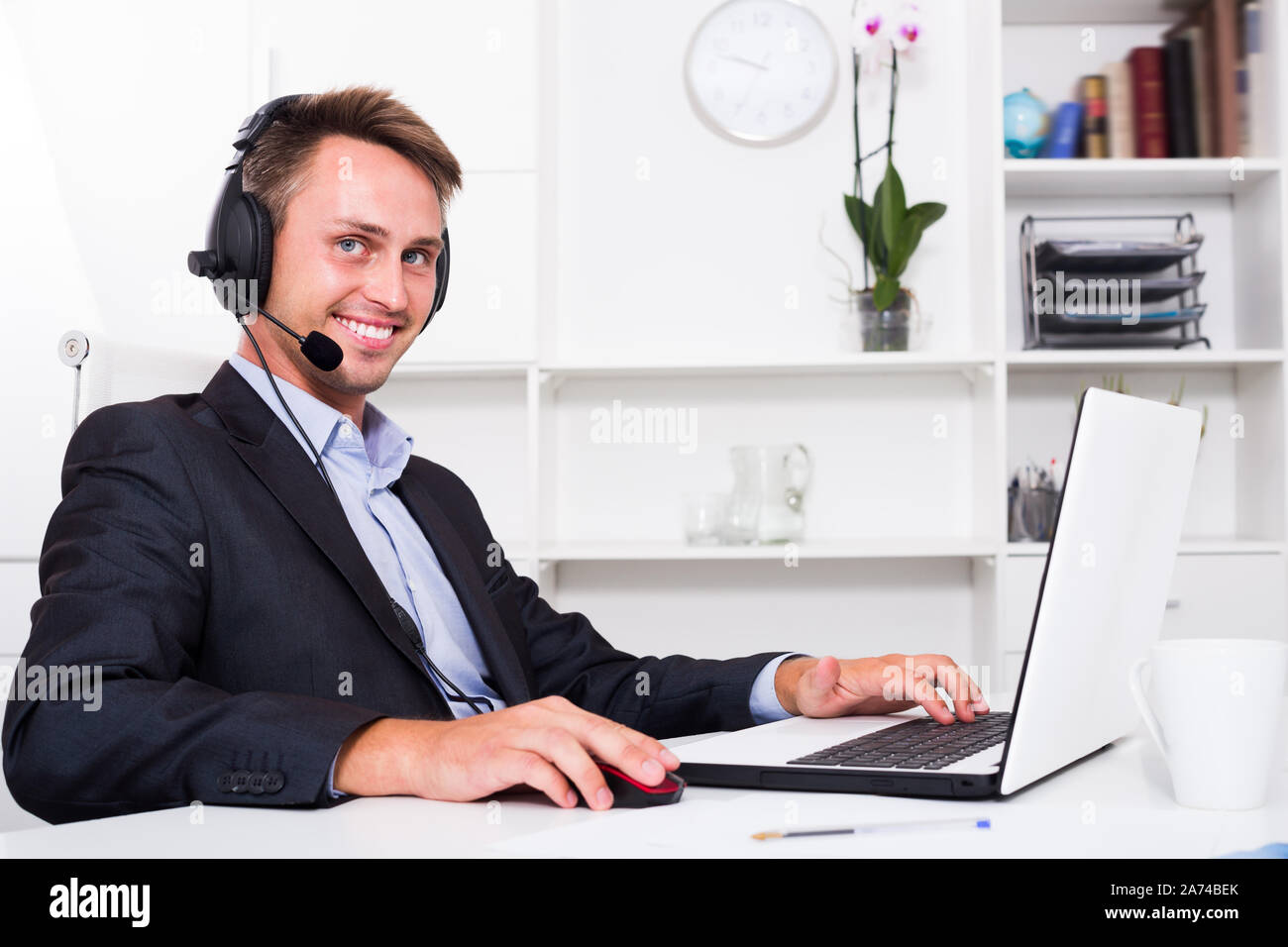 Positive young man talking on headset at company office Stock Photo - Alamy
