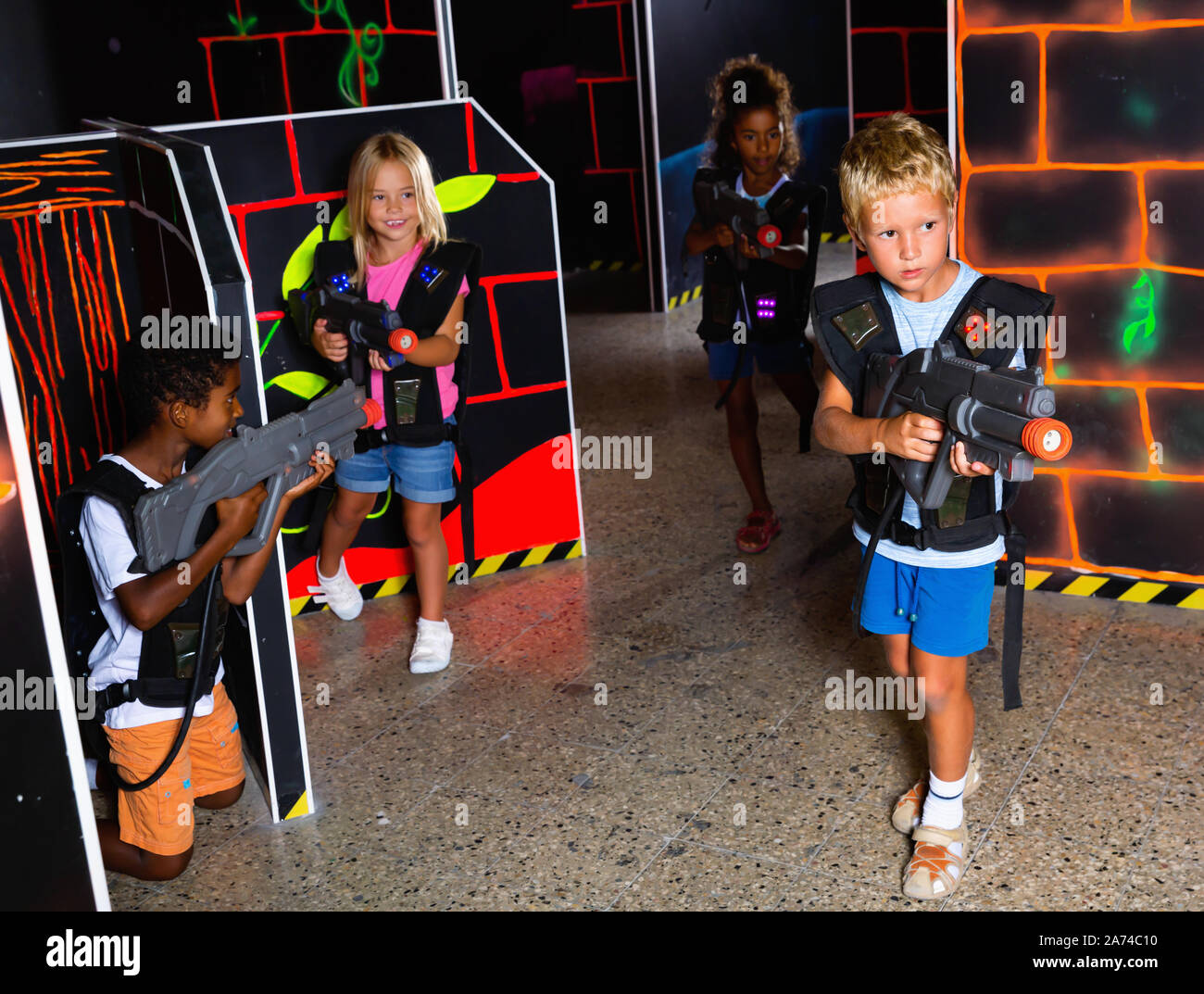 Multiracial team of cheerful positive smiling tween kids aiming laser ...