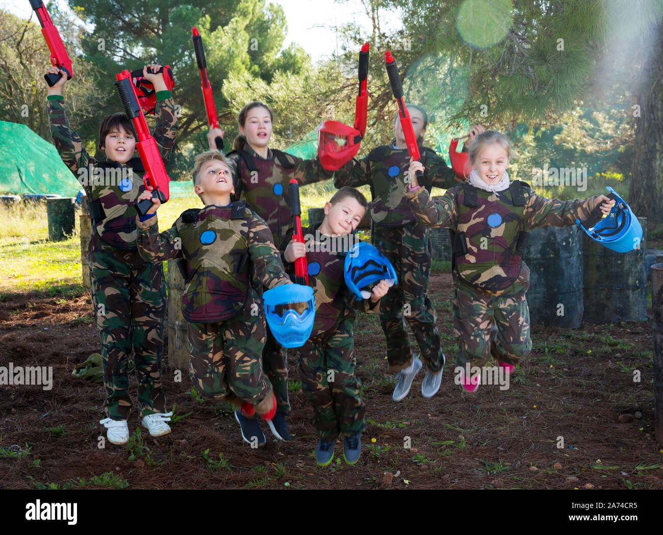 Portrait of satisfied boys and girls paintball players jumping having ...
