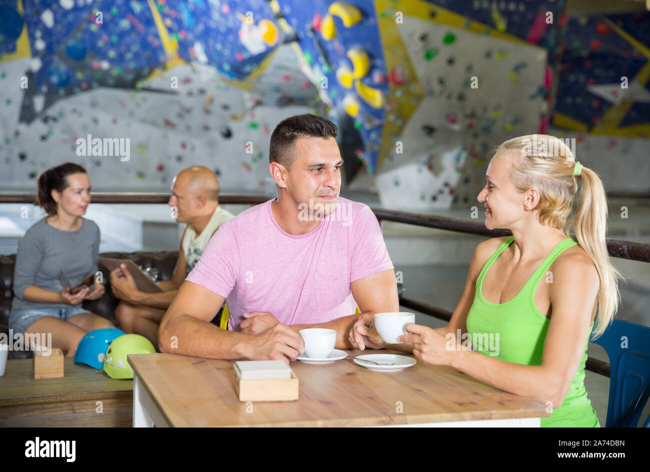 Portrait of happy athletic young people drinking coffee on break during ...