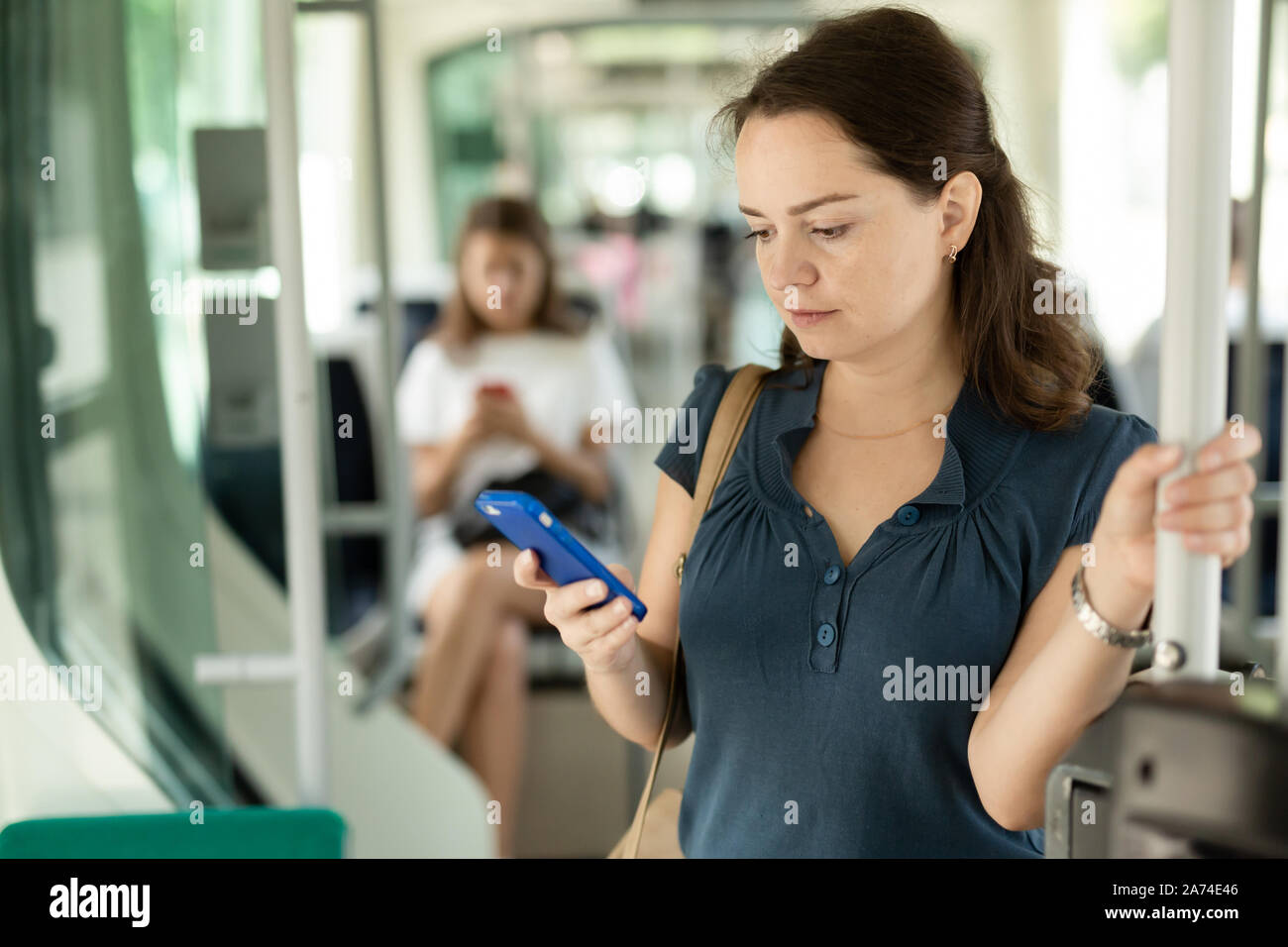 Woman using mobile phone in the cabin of a bus or tram Stock Photo - Alamy