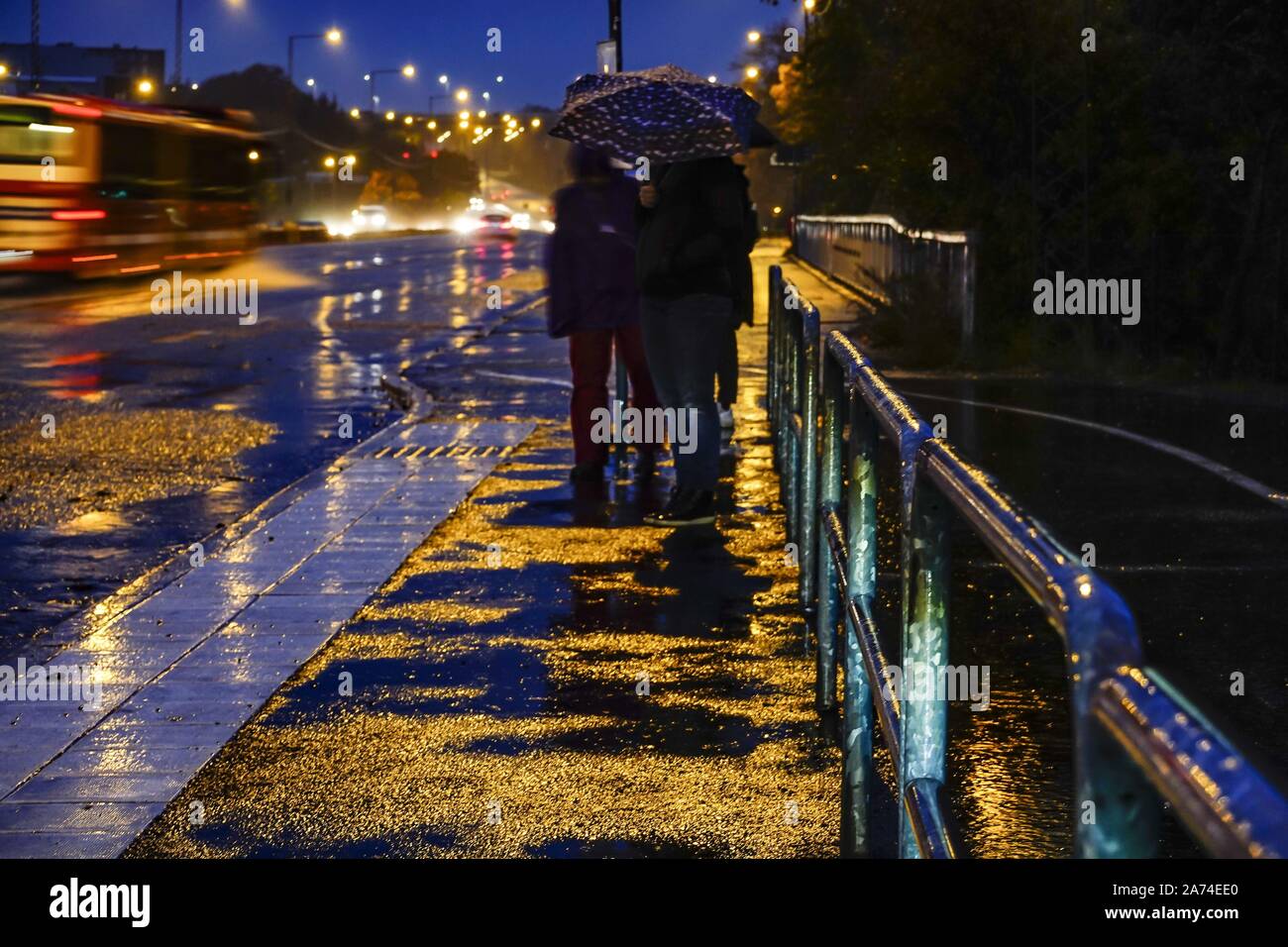 Stockholm, Sweden A pedestrian with umbrella in the rain at a bus stop ...