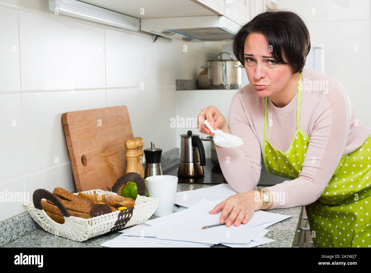 Miserable housewife reading banking statement and crying at kitchen ...