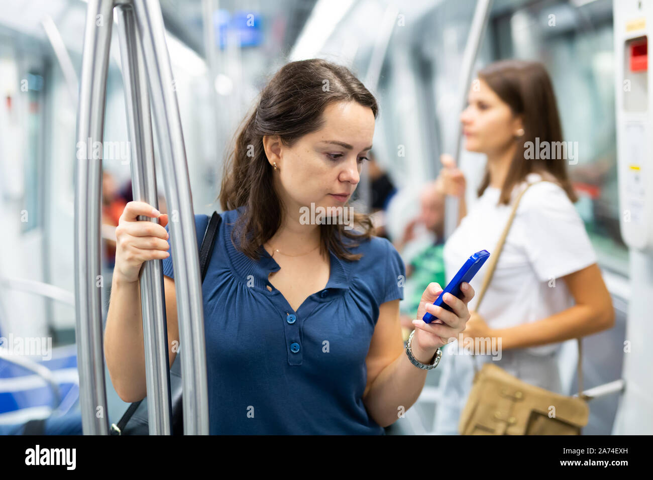 Positive woman reading from mobile phone screen in metro Stock Photo ...