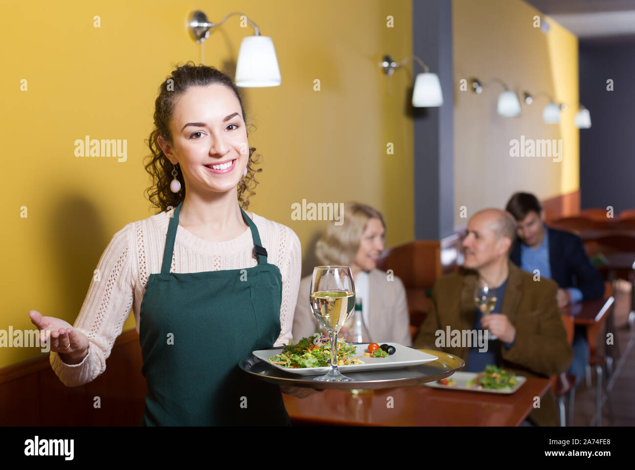 Adult young waitress greeting customers at table in restaurant Stock ...