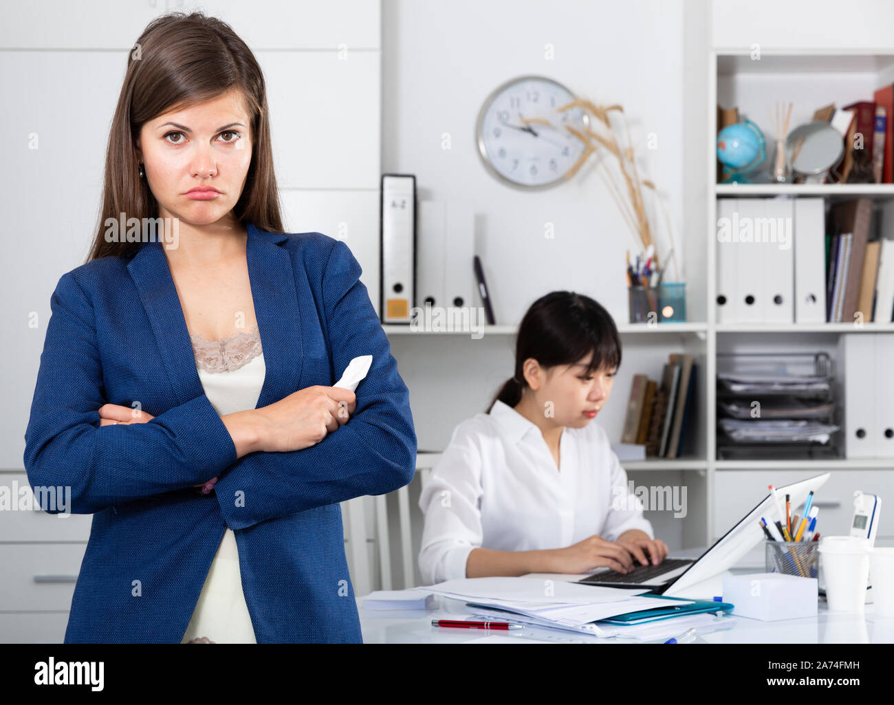 Frustrated woman standing at office on background with coworker Stock ...
