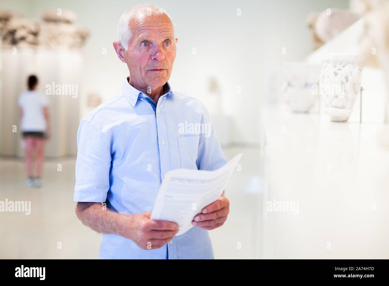 Attentive mature man observing sculptures exhibition in art museum ...