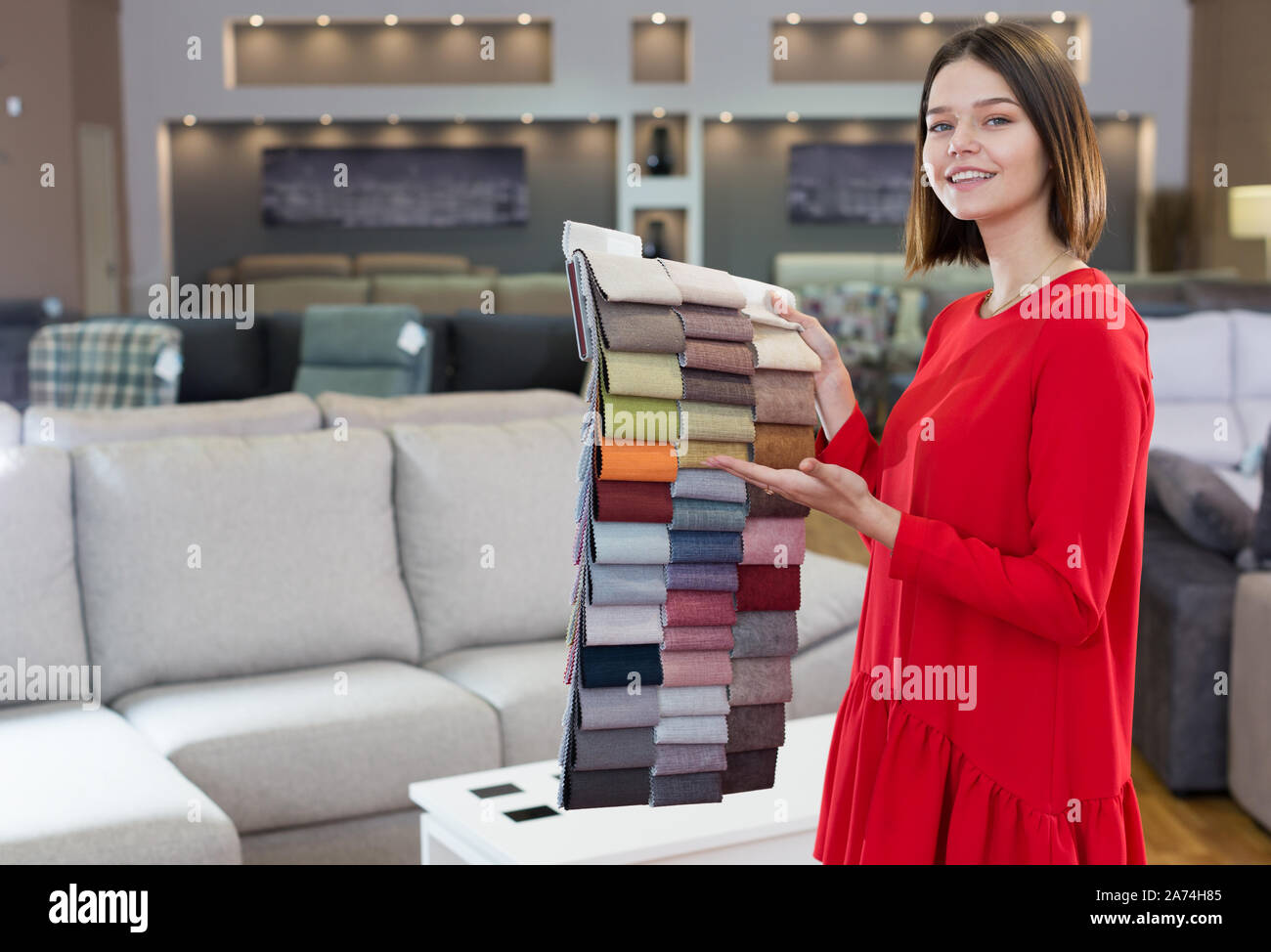 Friendly shop assistant demonstrating samples of upholstery fabric in ...
