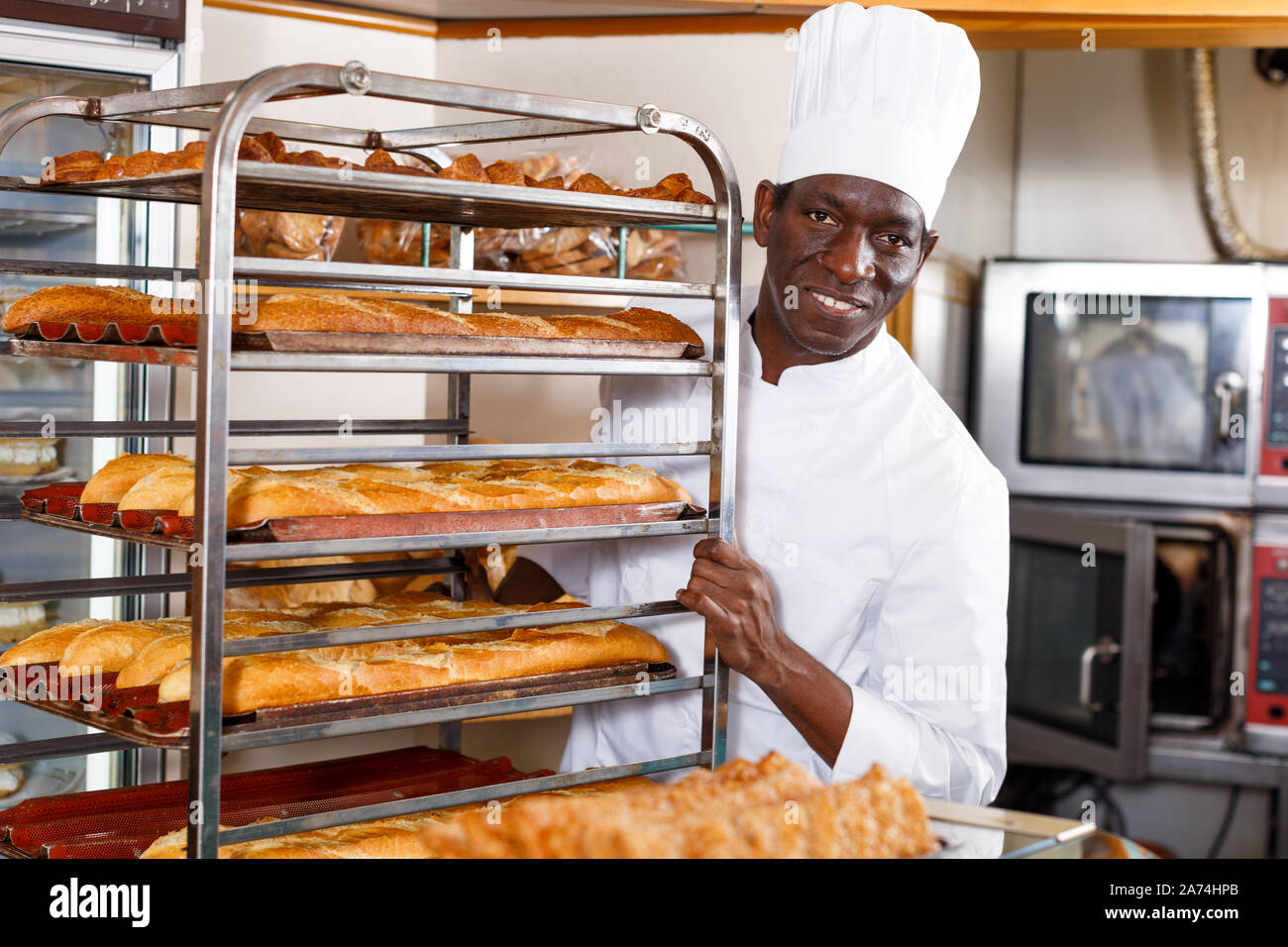 Skillful African American baker working in small bakery, carrying fresh ...