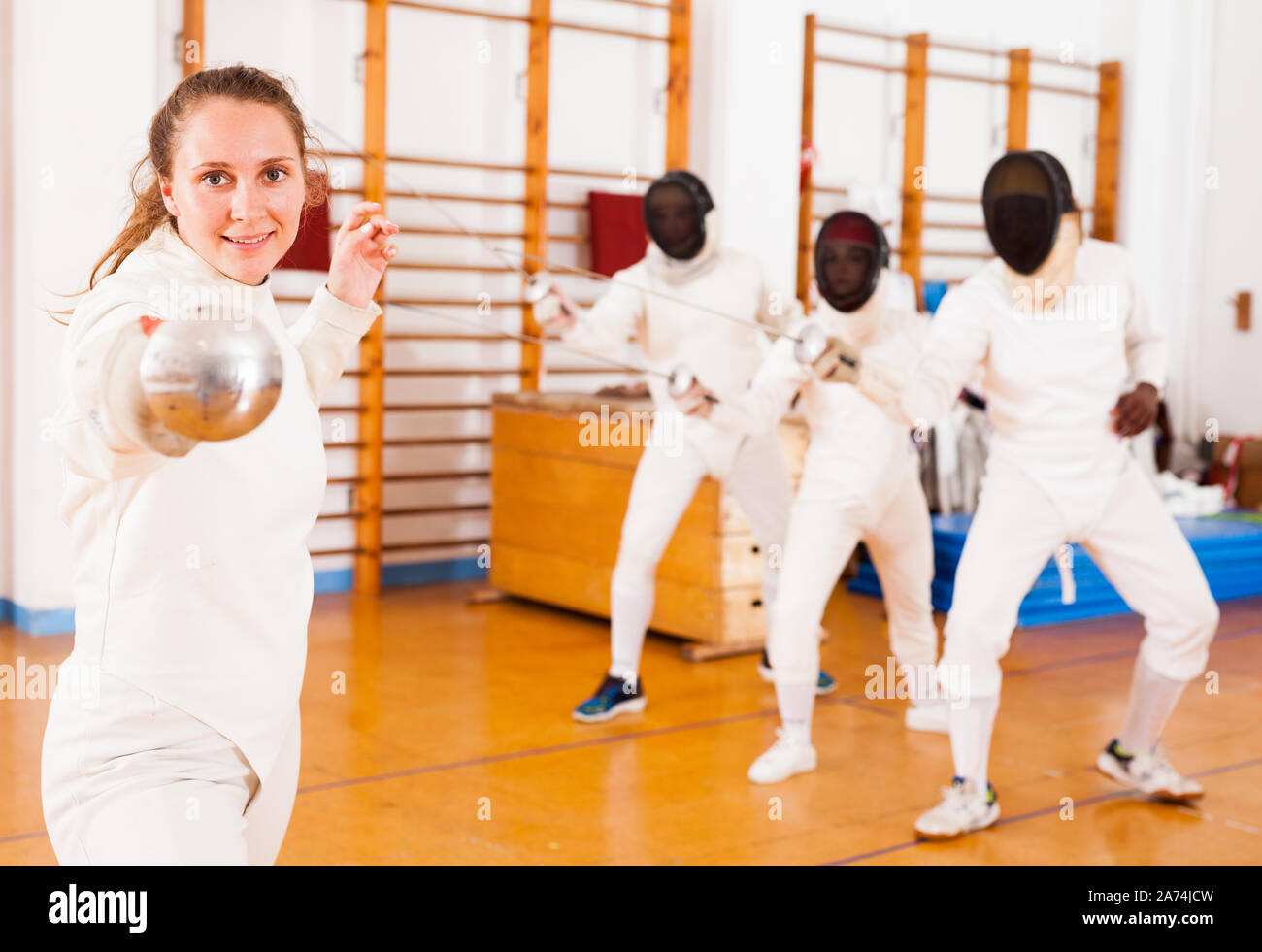 Sporty young female fencer practicing fencing technique in training ...