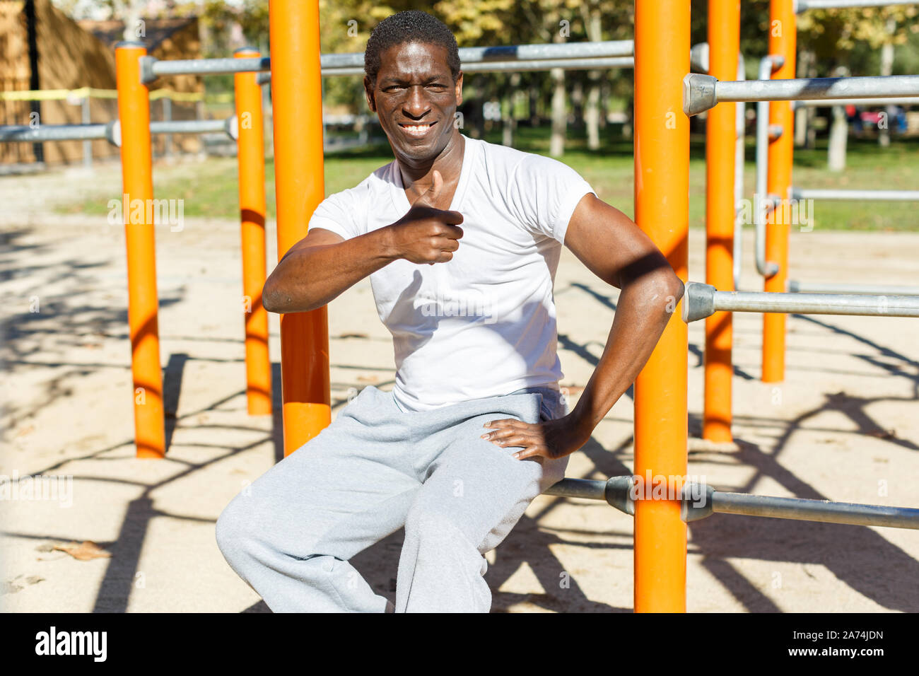 Athletic african american male performs warm-up exercises at chin-up ...