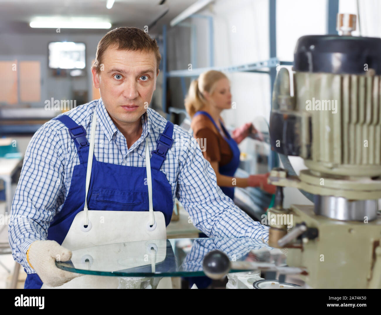Adult male worker of glass factory engaged in processing of curved ...
