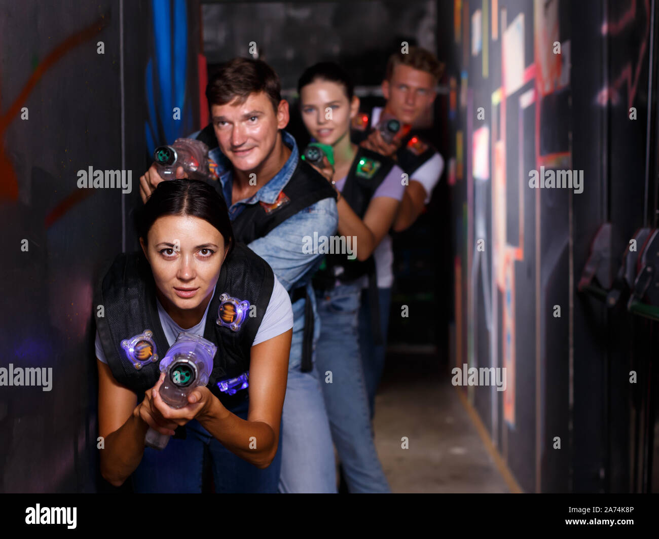 Group adult emotional people with laser guns playing laser tag game ...