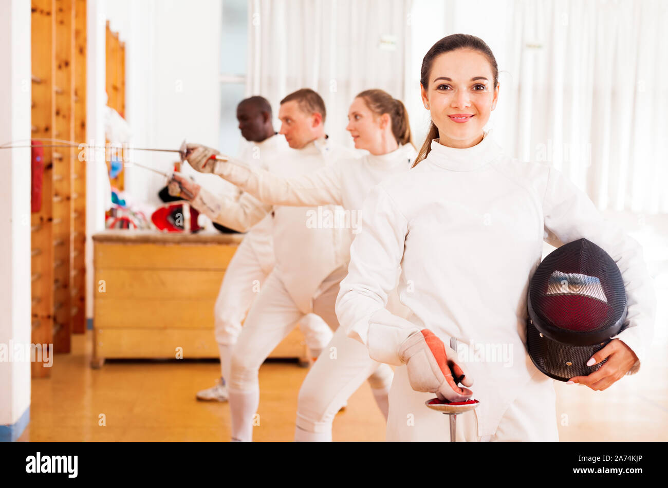 Positive active young female fencer standing at fencing workout Stock ...