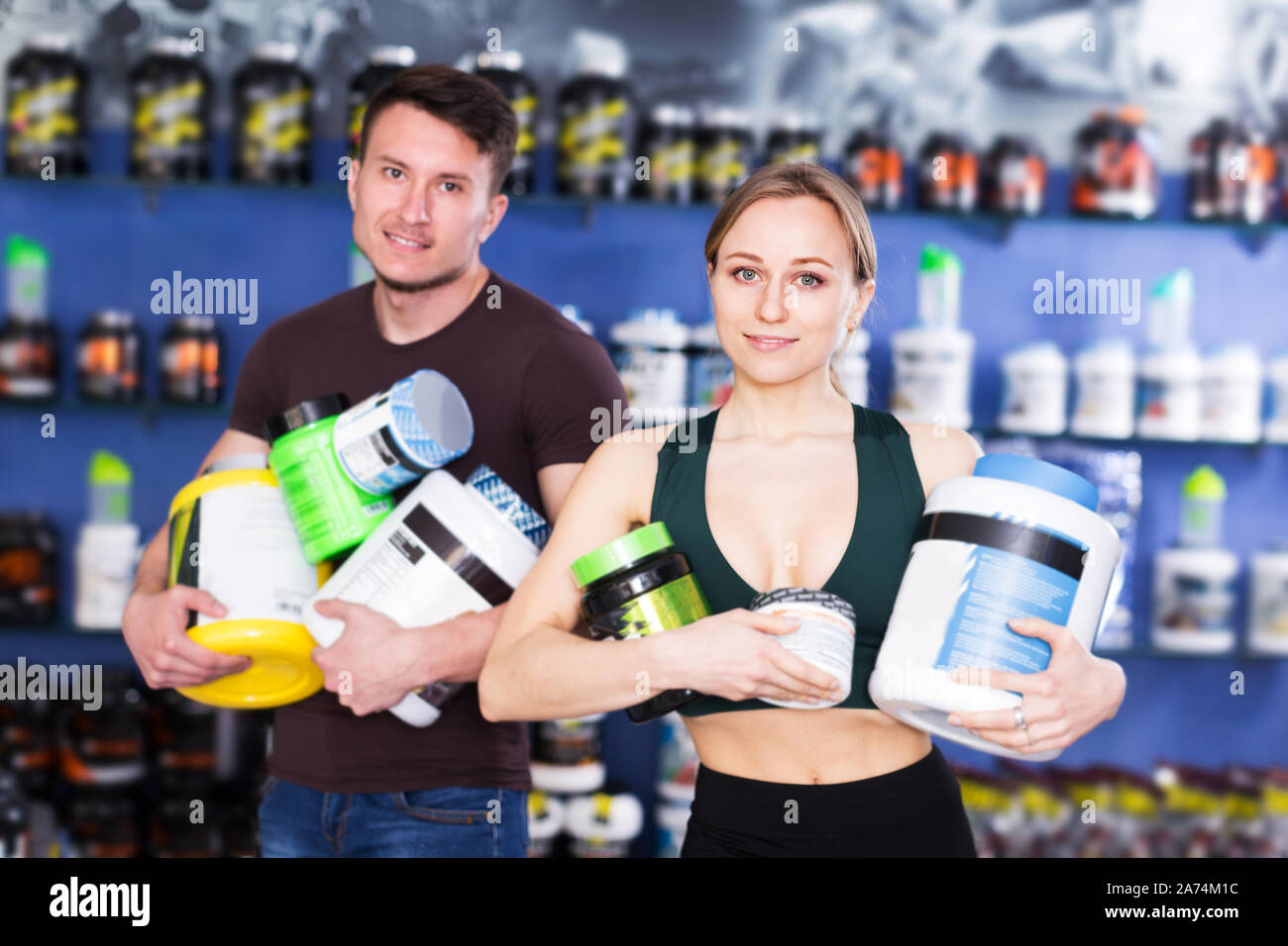 Positive fit people holding plastic jar of sport food supplements in ...