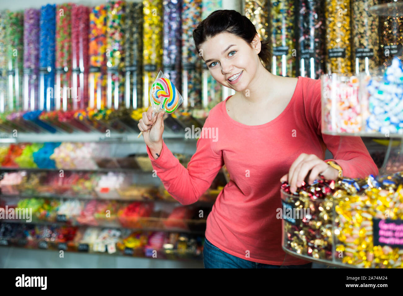 Happy brunette girl buying candies at shop Stock Photo - Alamy