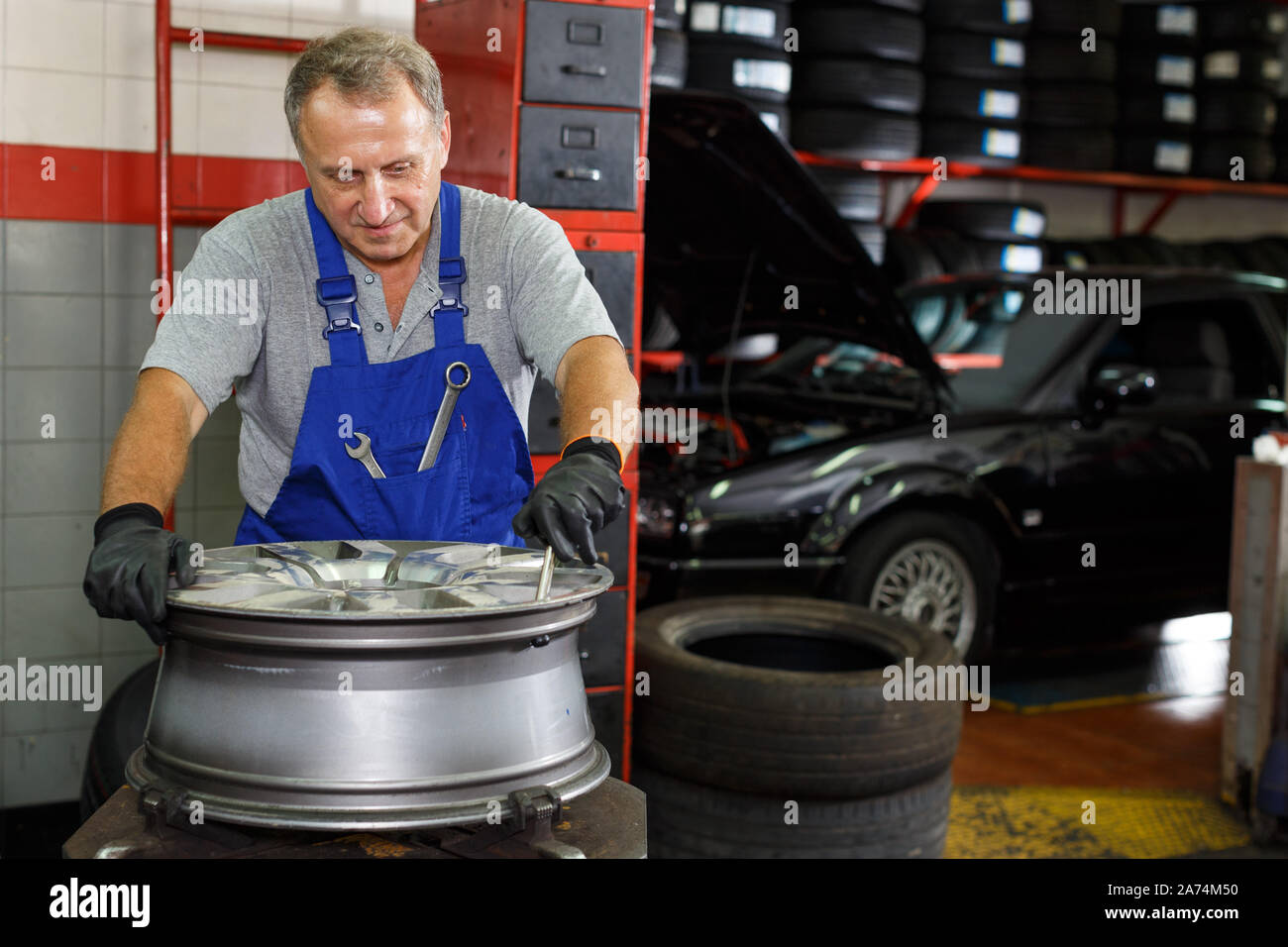 Qualified mechanic of service station straightening rim and repairing ...