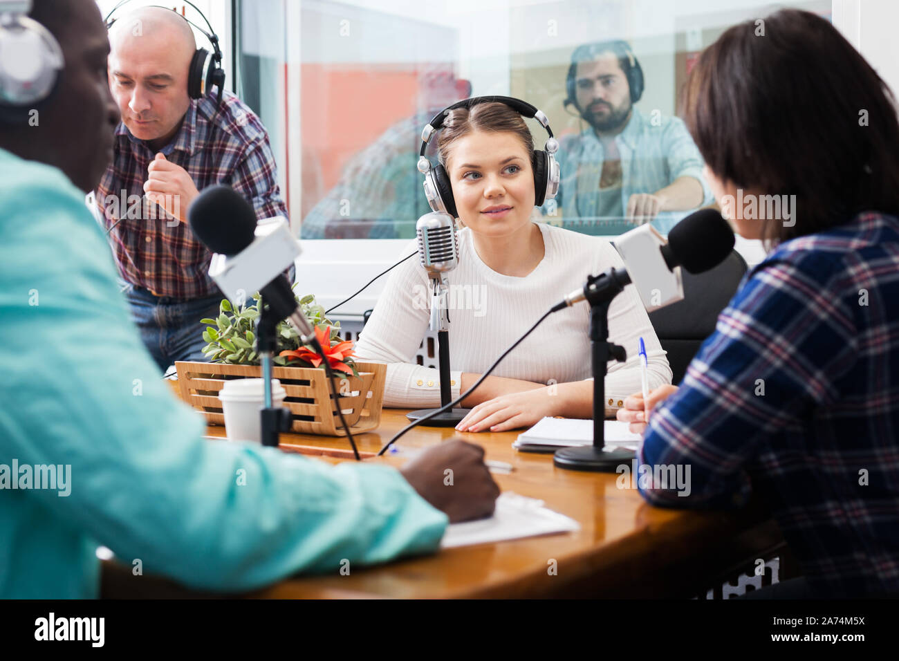 Positive international team of radio hosts discussing with guest in ...