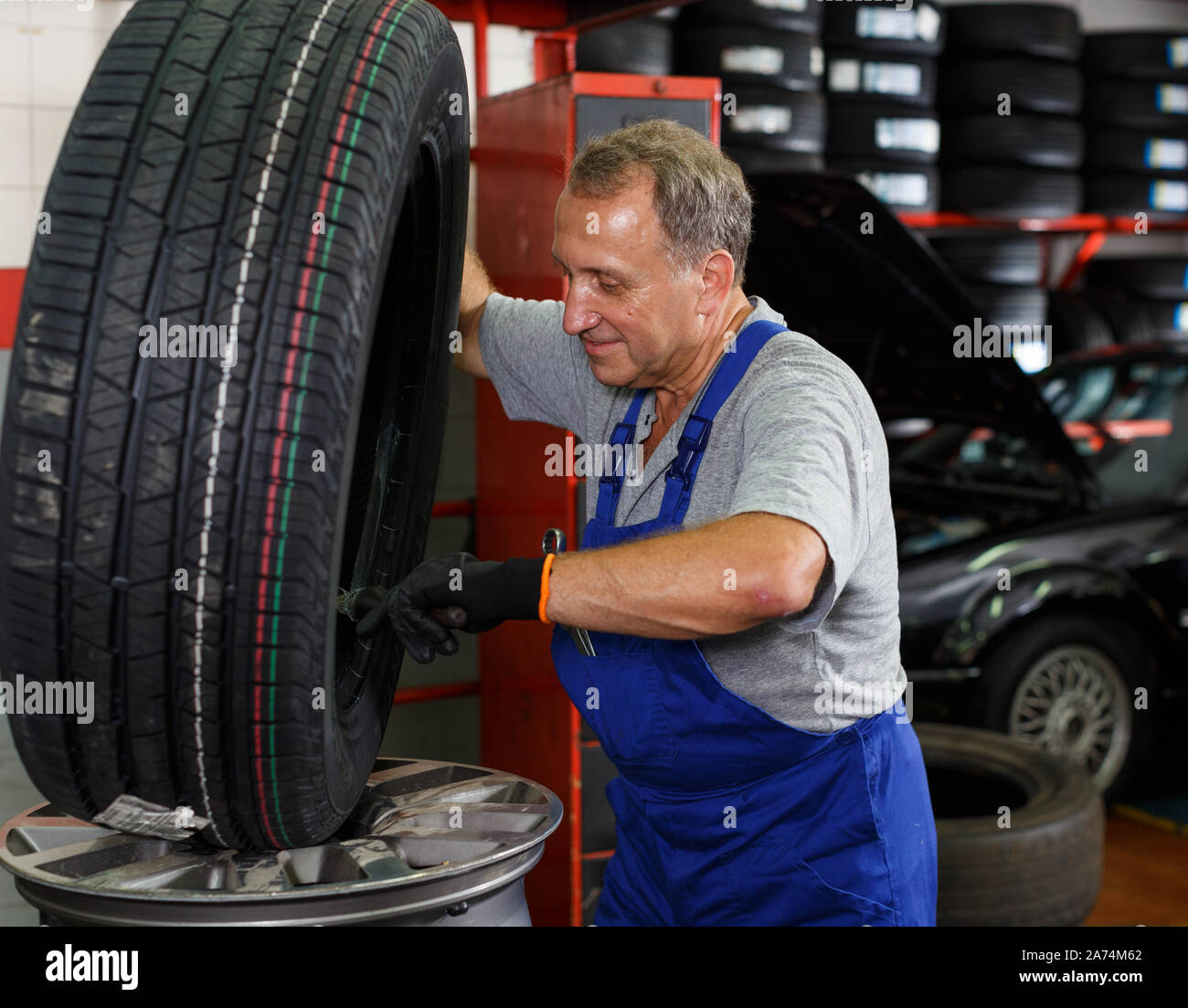 Professional male mechanician restoring tire and disc of car wheel in ...