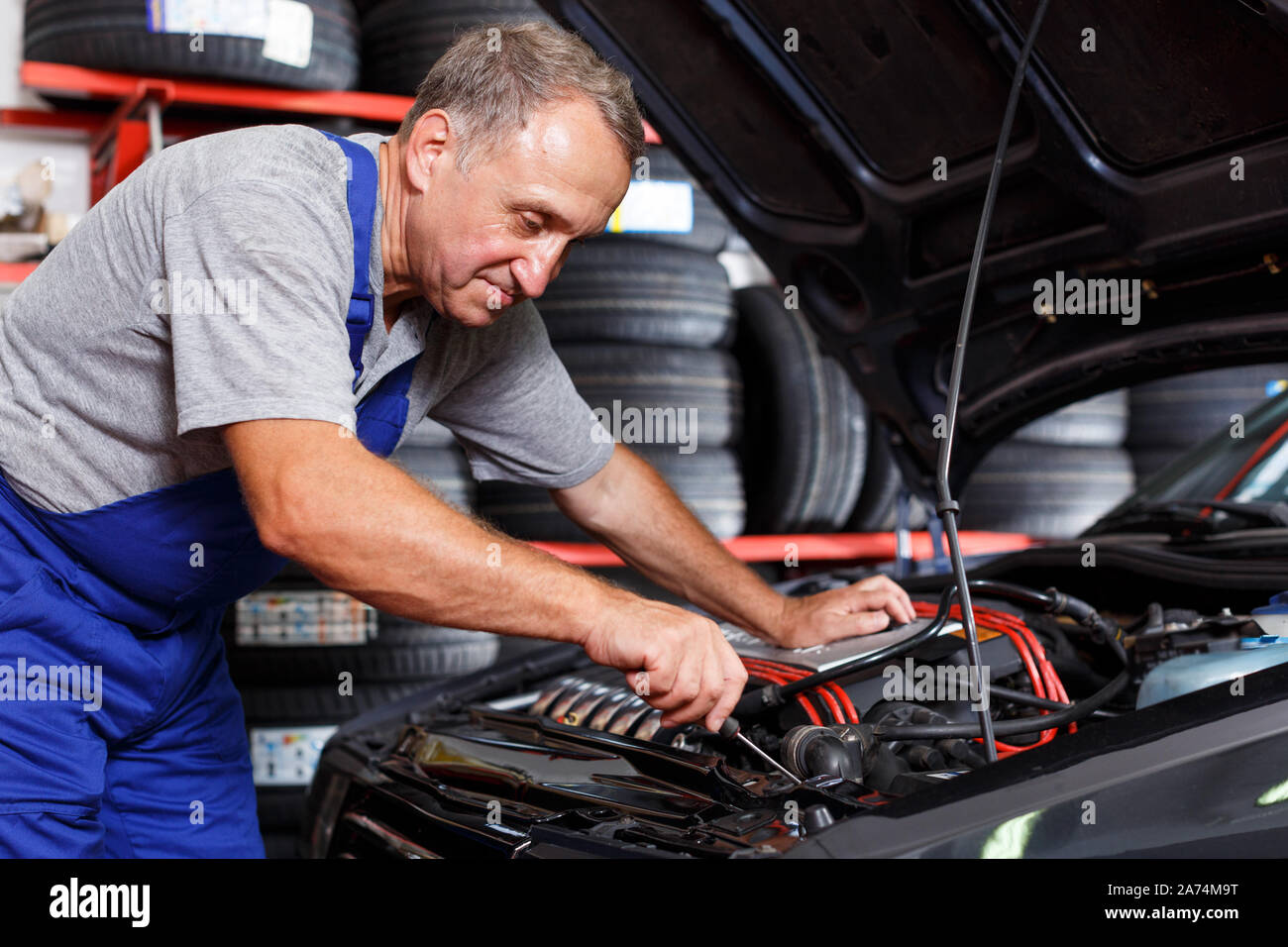 Professional mature man car mechanician repairing car in auto repair ...