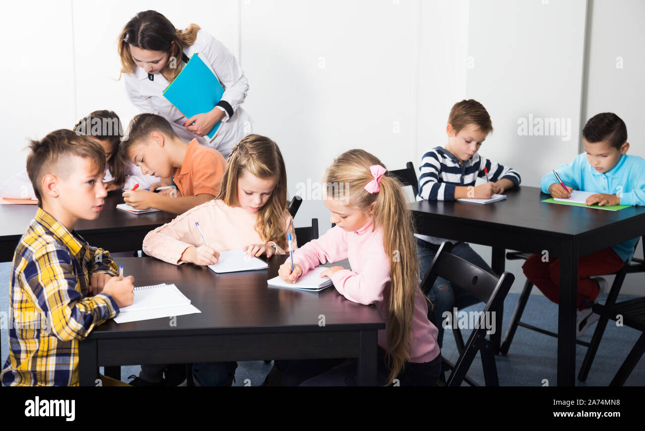Positive little boys and girls with teacher drawing in classroom Stock ...